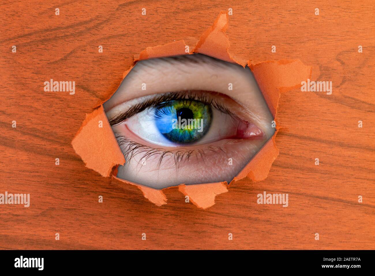 close up of eye looking through the torn paper hole Stock Photo - Alamy