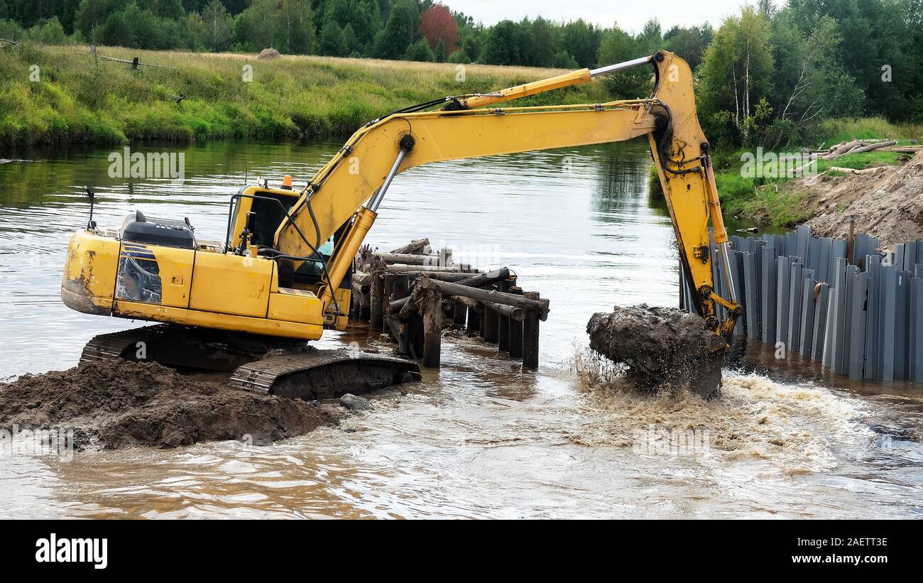 Excavator working in the small forest river, excavator bucket ...