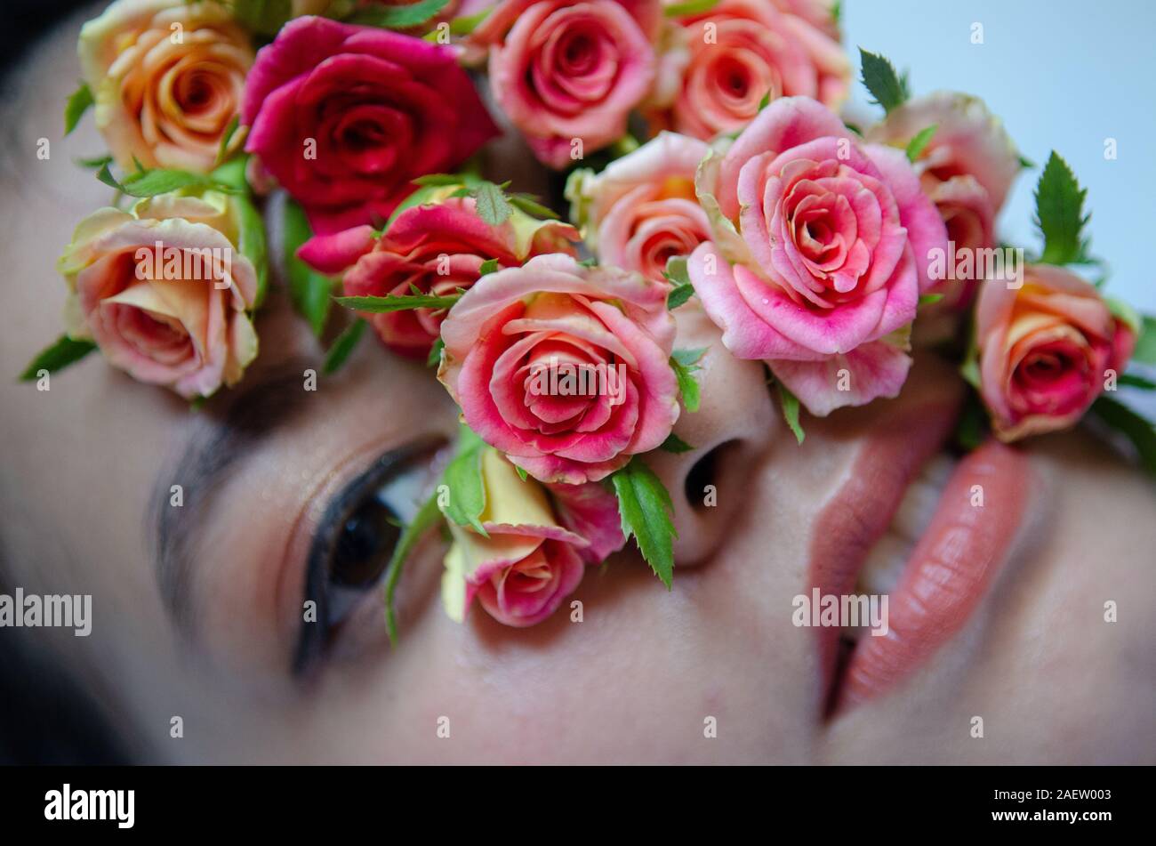 A young woman poses with roses on her face in a creative photoshoot ...