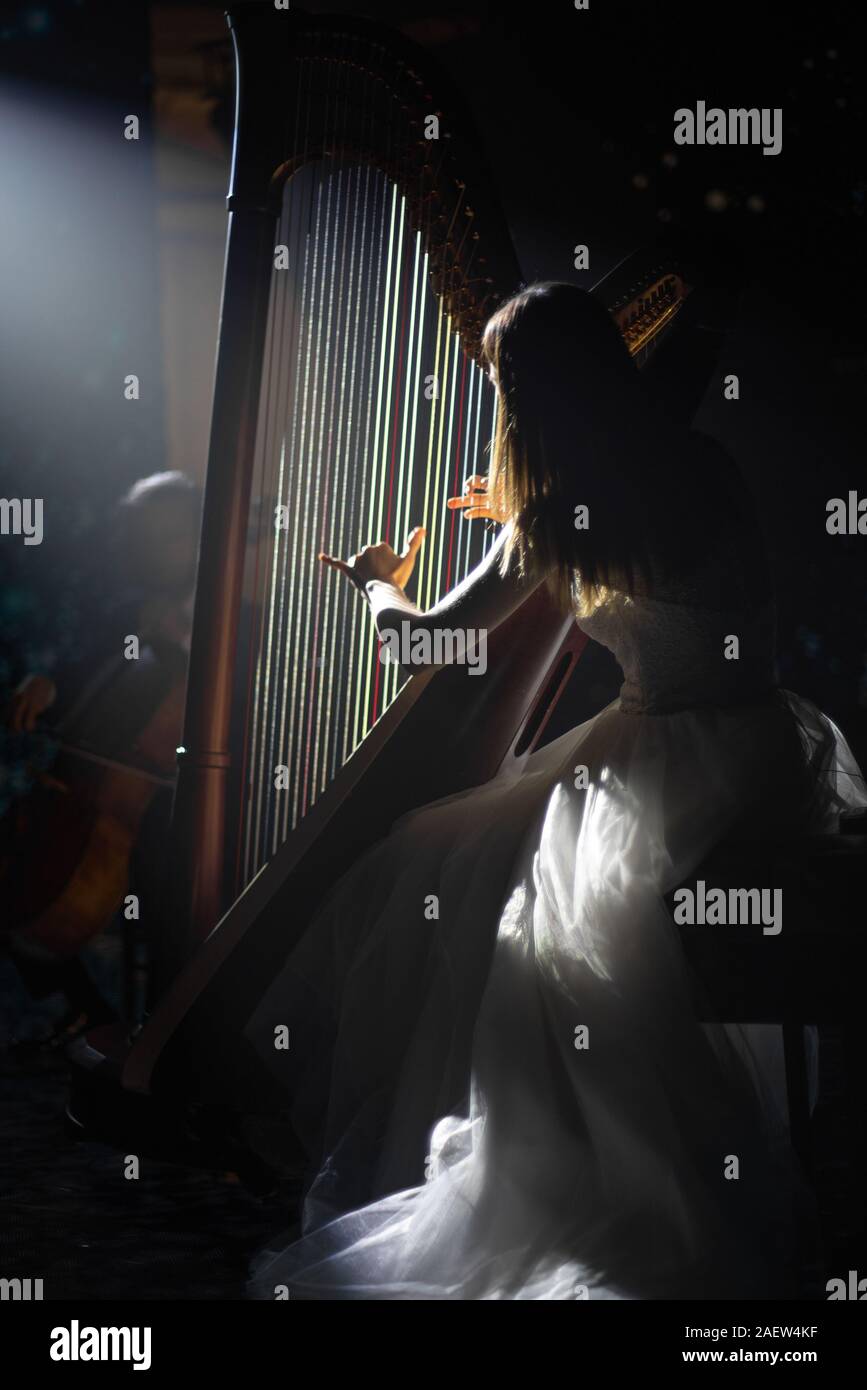 girl playing the harp on stage during a concert Stock Photo - Alamy