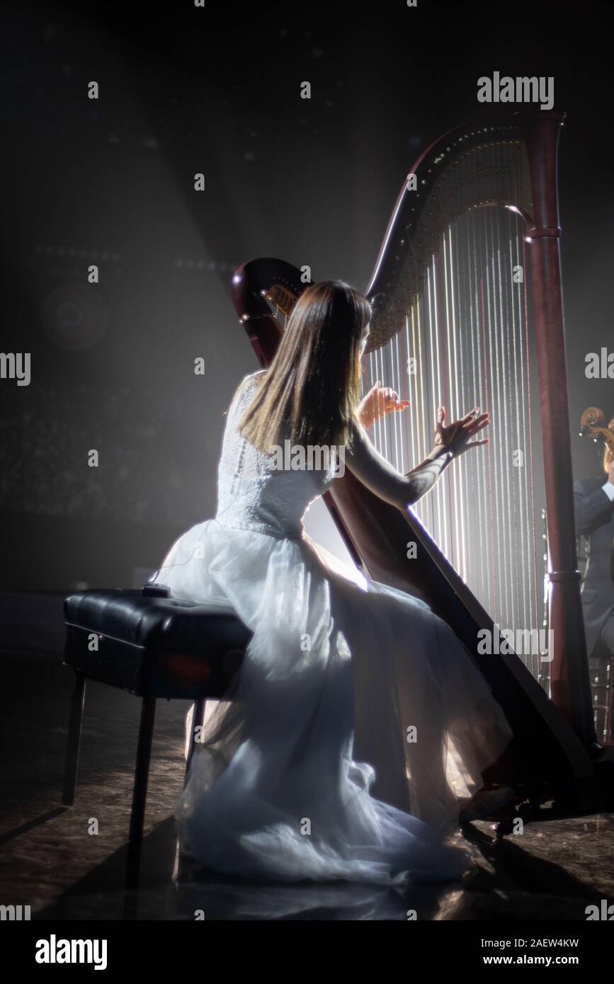 girl playing the harp on stage during a concert Stock Photo - Alamy