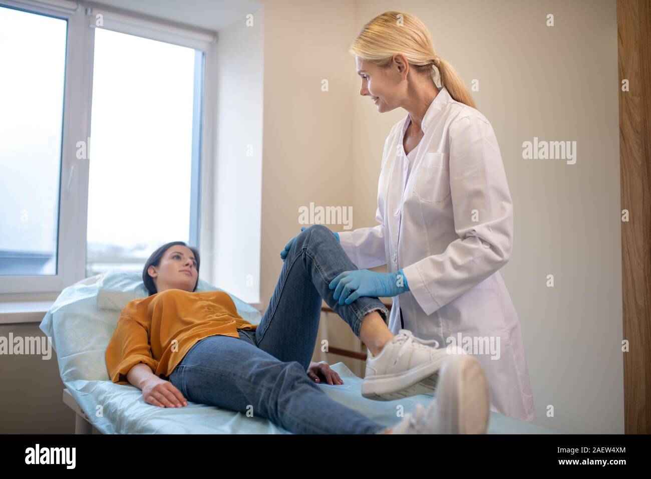 Blond doctor wearing sterile gloves working with patients leg Stock ...
