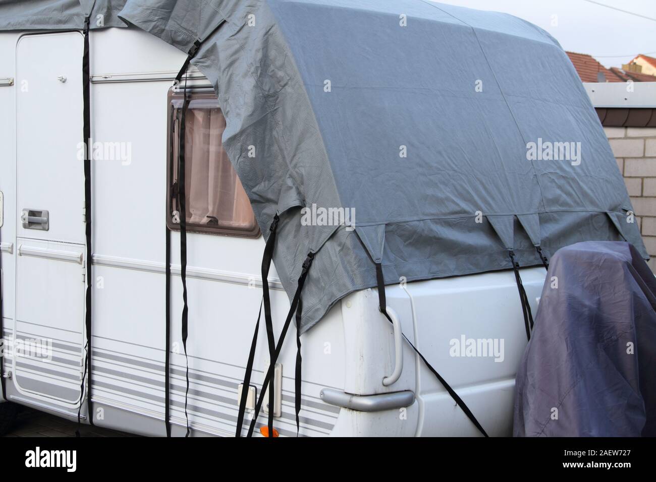 a caravan with a gray tarpaulin Stock Photo - Alamy