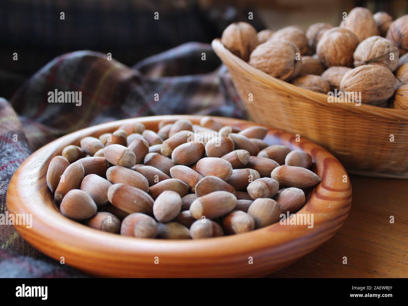 A bowl full of hazel nuts with a basket full of walnuts, in close up ...