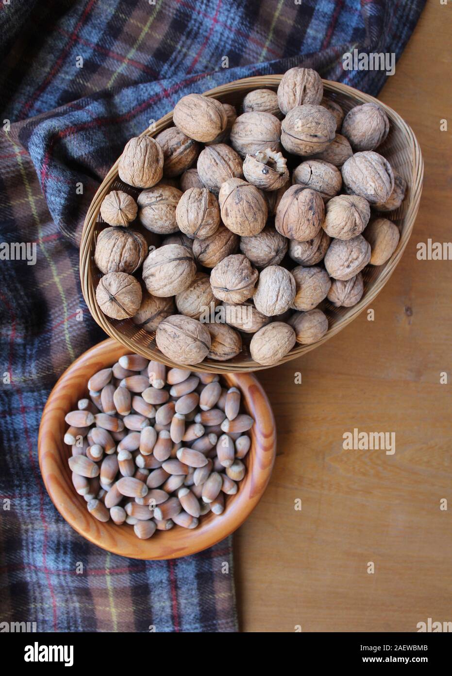 Top down view of a basket of walnuts in shells, and a wooden bowl with ...