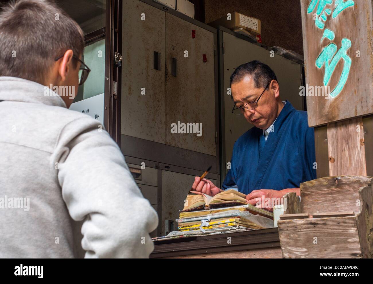 Henro pilgrim, and priest writing temple name in nokyocho pilgrimage ...