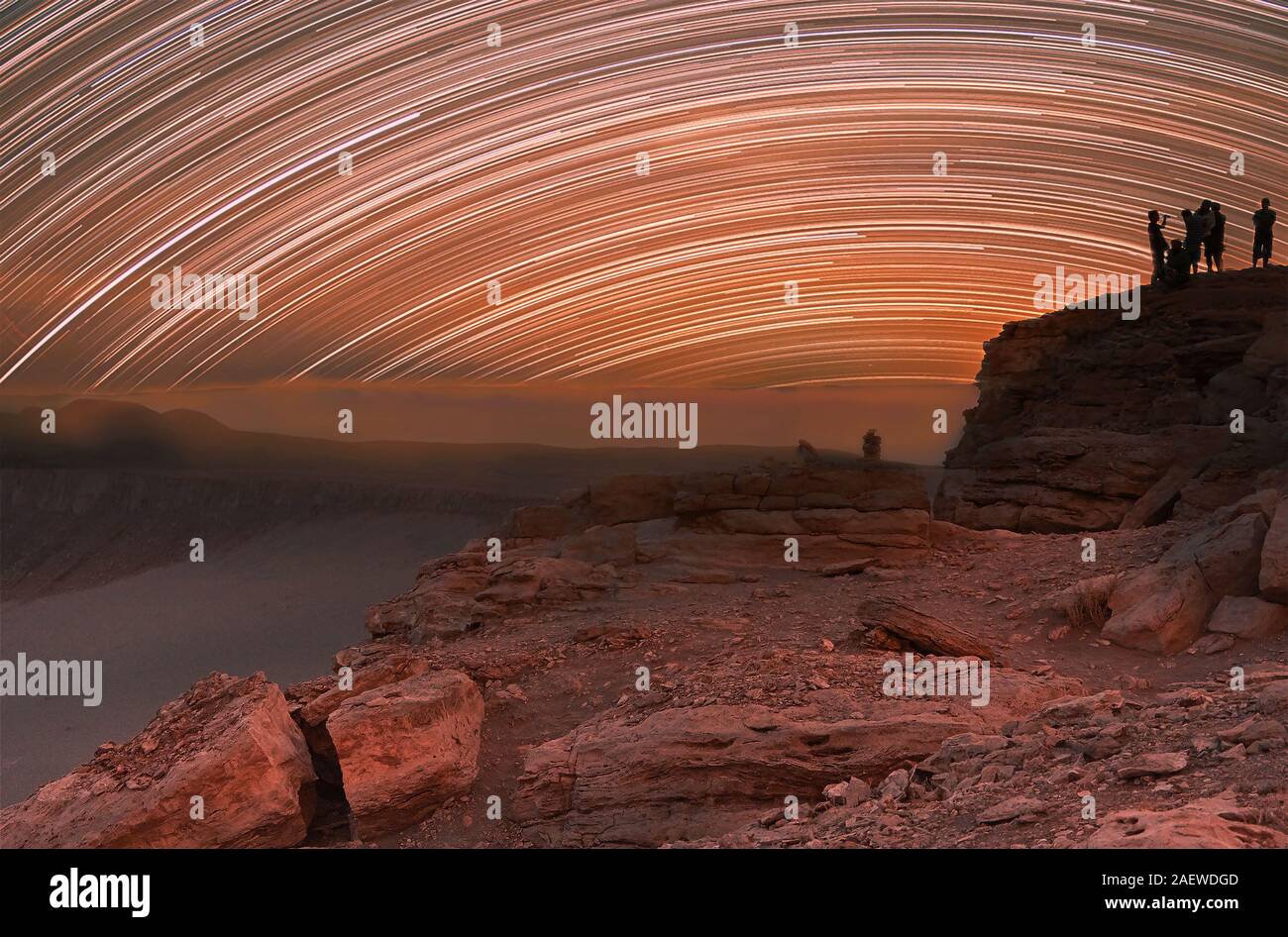 Young people is on the rock. Night glowing stars trails in the sky ...