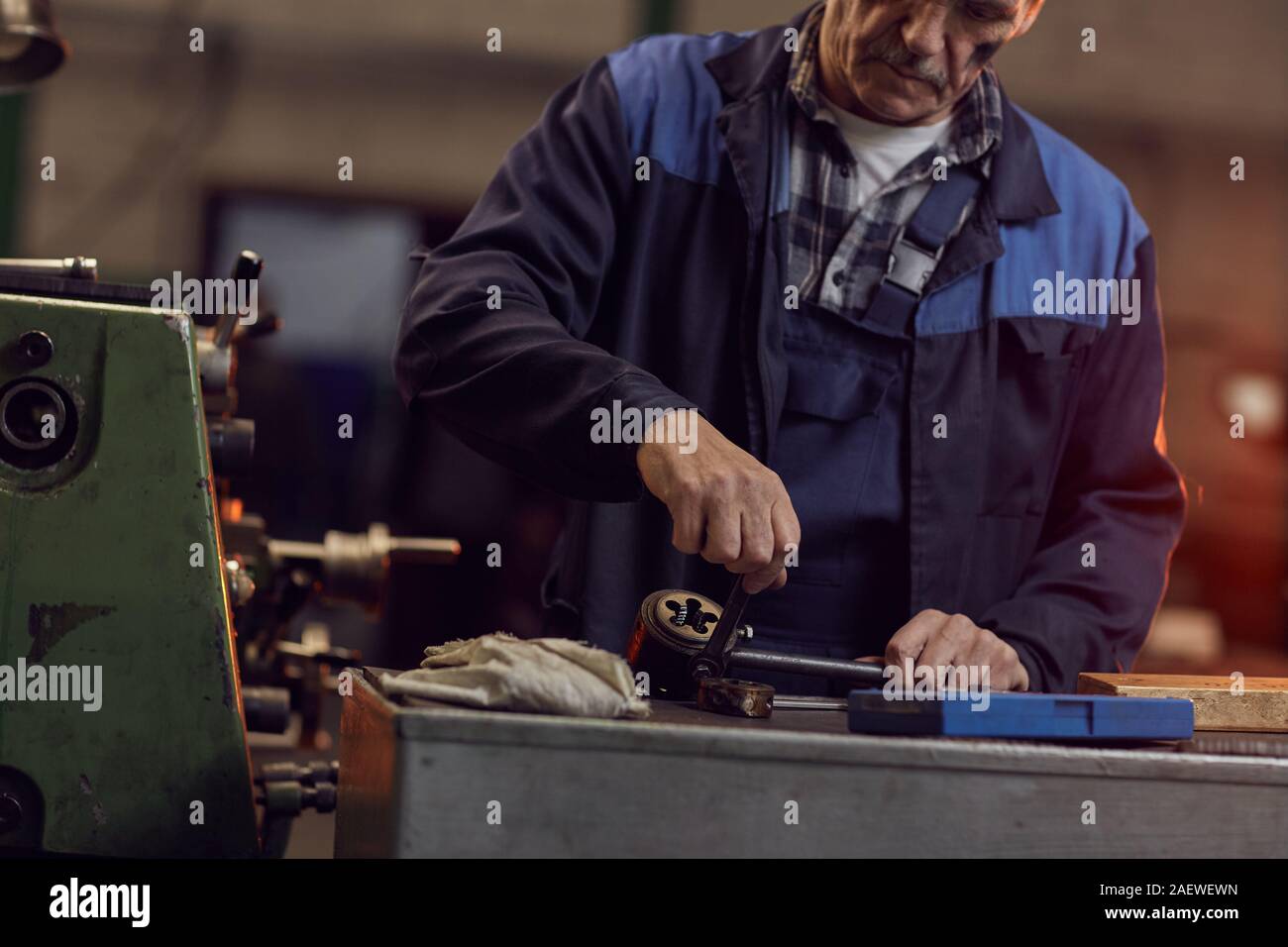 Close-up of repairman in work wear standing and repairing the details ...