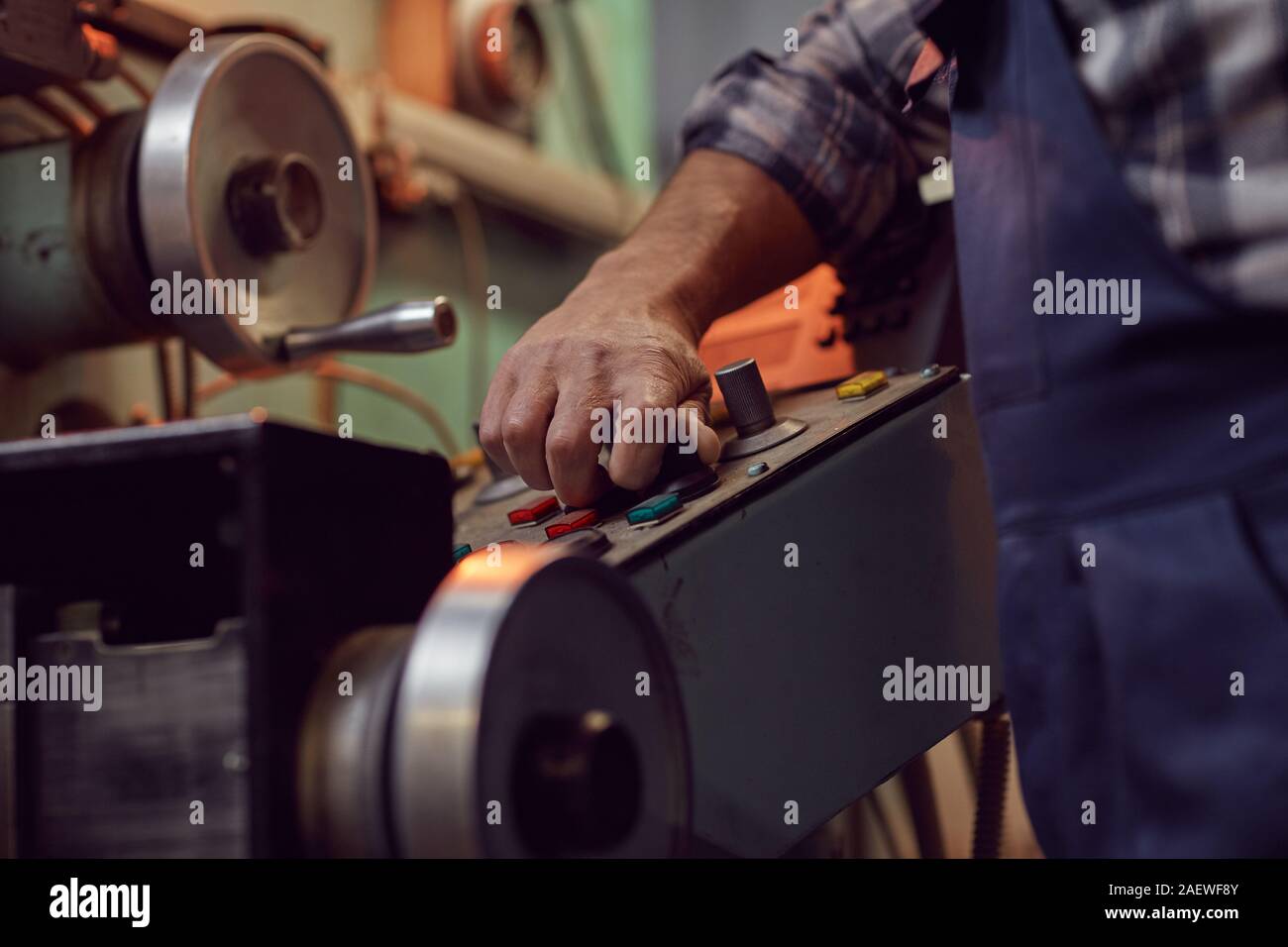 Close-up of operator in overalls controlling the work of machine using ...
