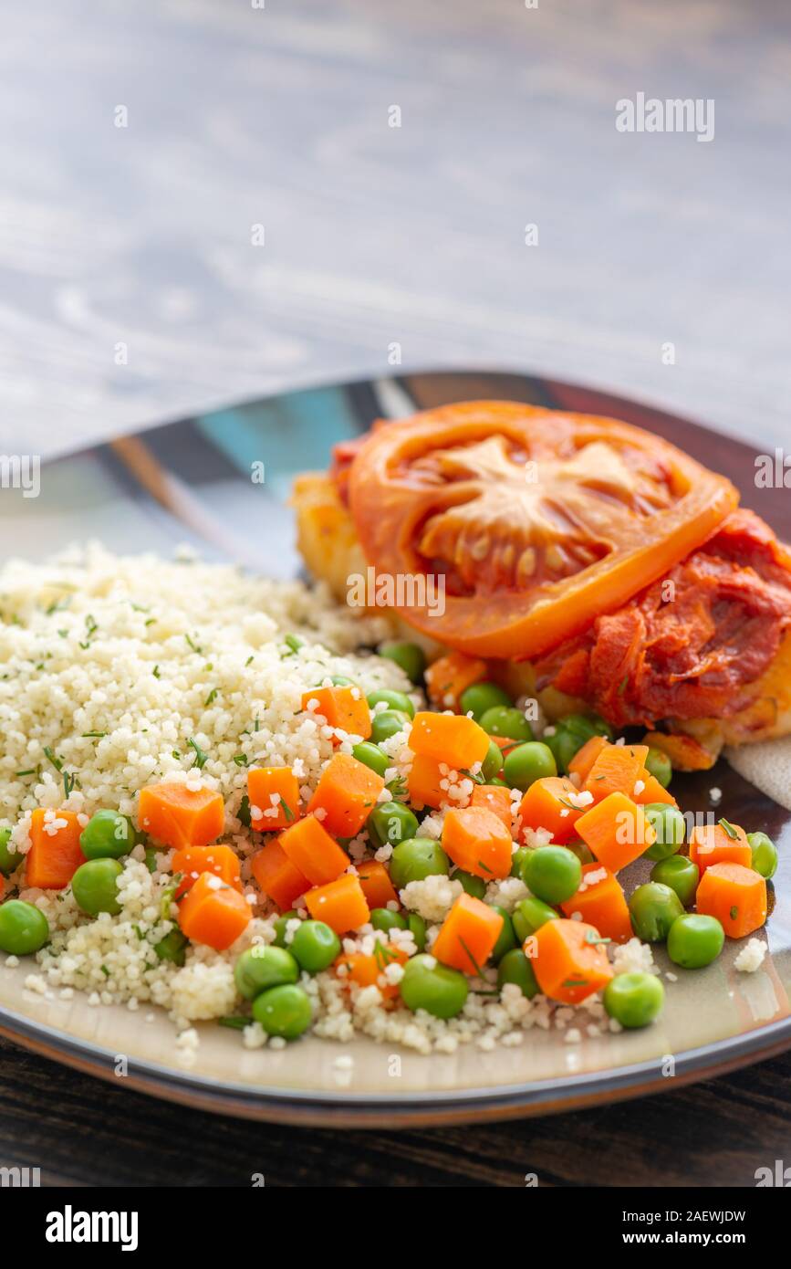 Fish, couscous and vegetables in plate wood background Stock Photo - Alamy
