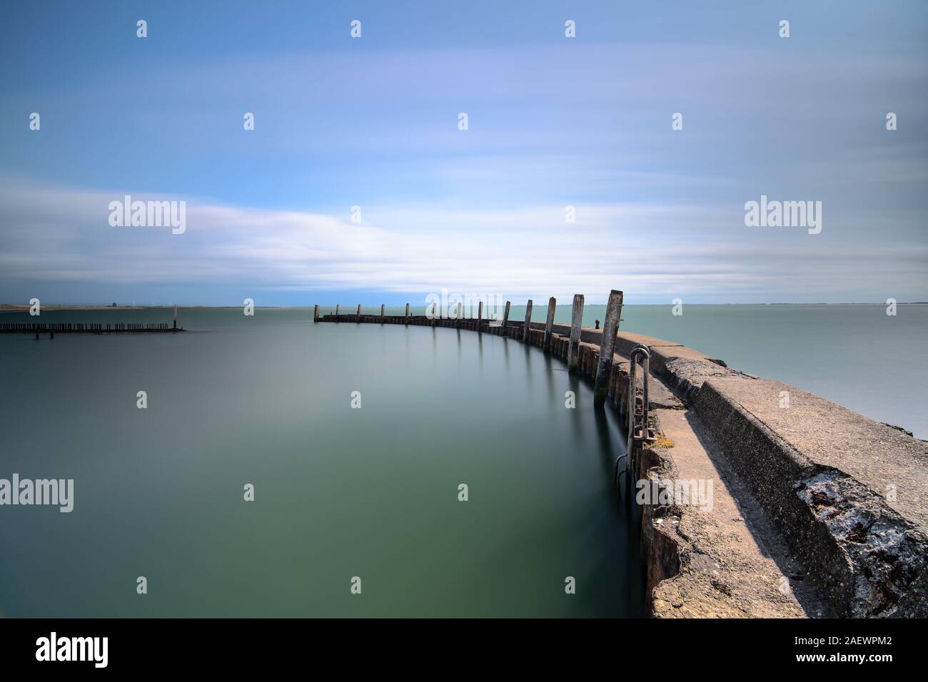 Weathered concrete breakwater with a rusty sheet pile and angled wooden ...