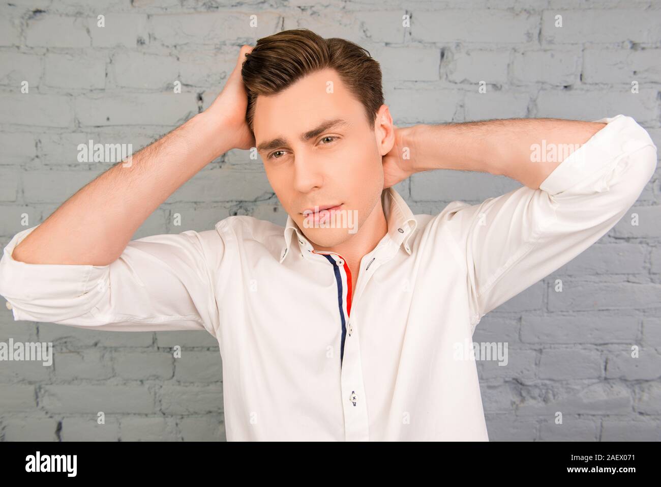 Attractive man touching his hair on the background of gray wall Stock ...