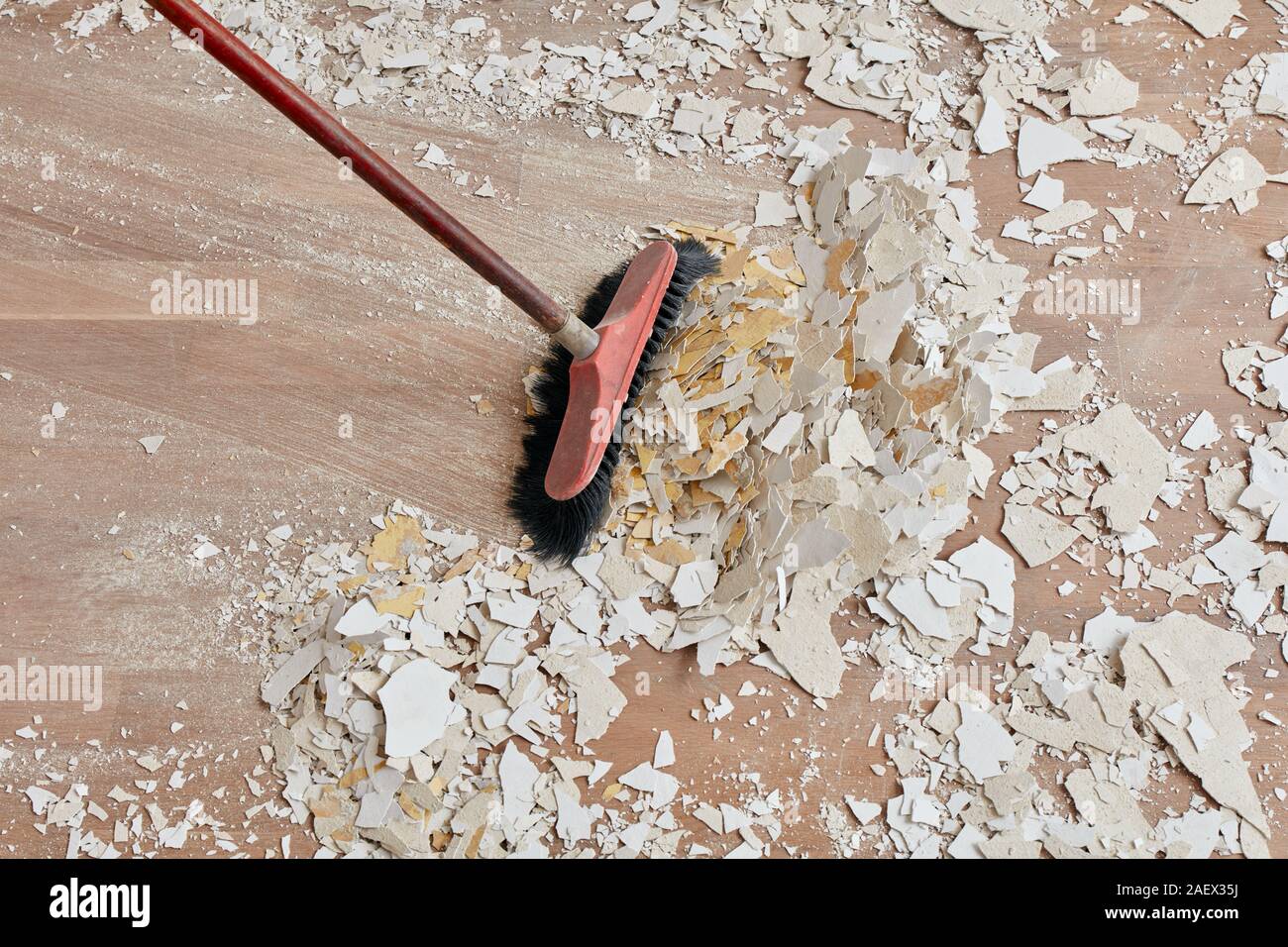 Builder sweeping the wooden floor after renovation Stock Photo - Alamy
