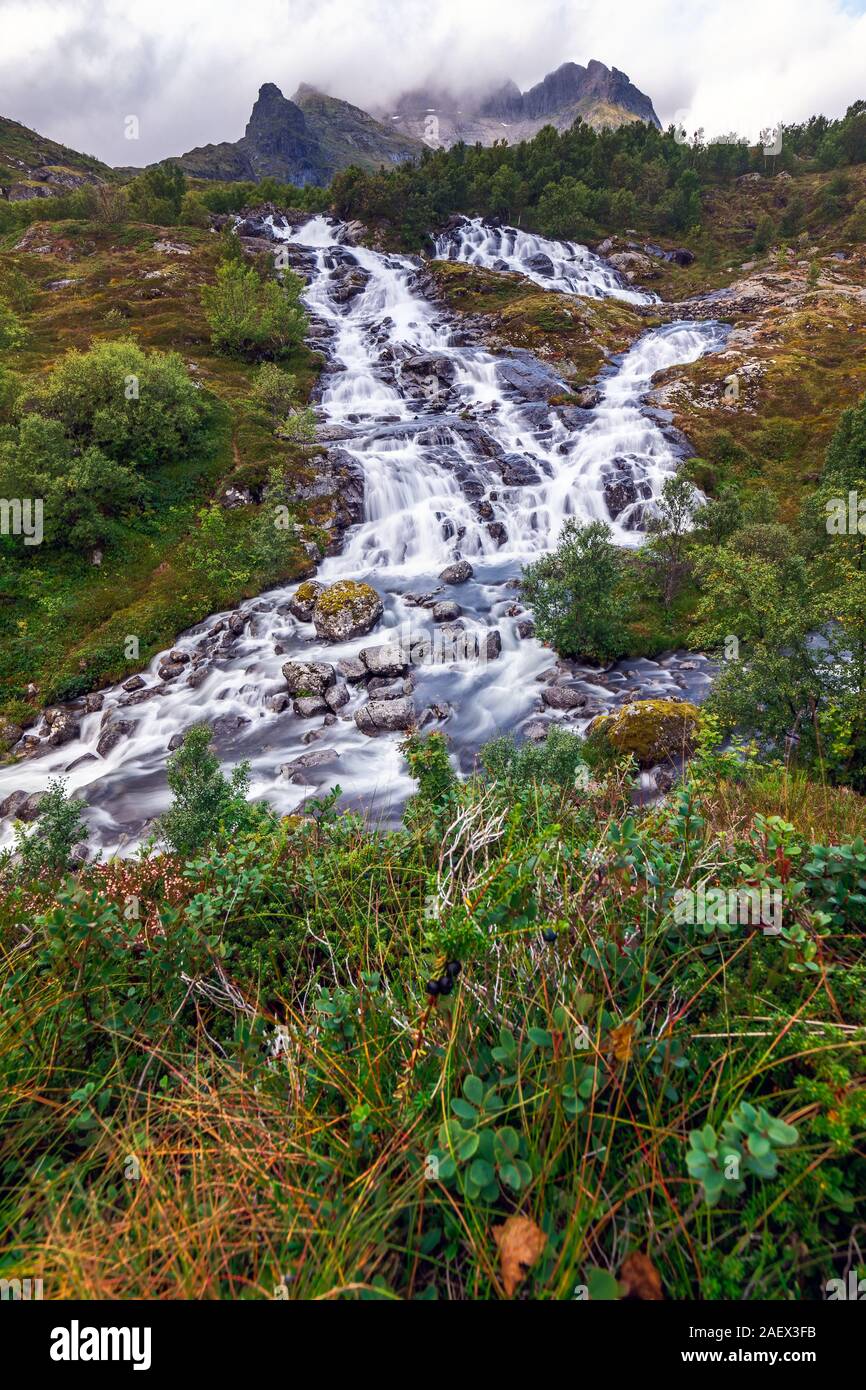 Beautiful waterfall among the autumn forest and mountains. on the road ...