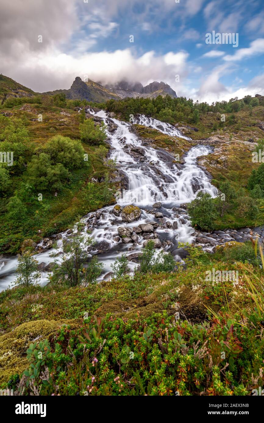 Beautiful waterfall among the autumn forest and mountains. on the road ...
