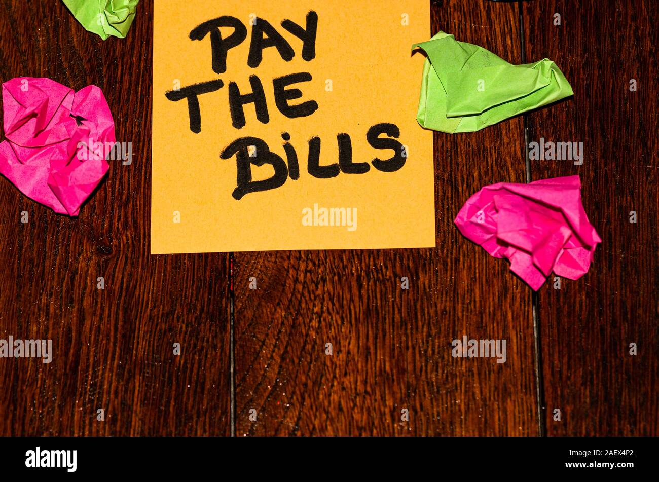 Writing on colorful sticky note Pay the bills and crumpled colorful ...