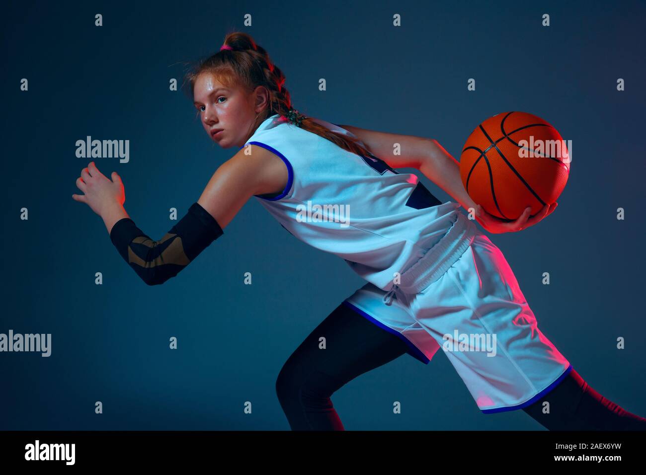 Flexibility. Young caucasian female basketball player on blue studio ...