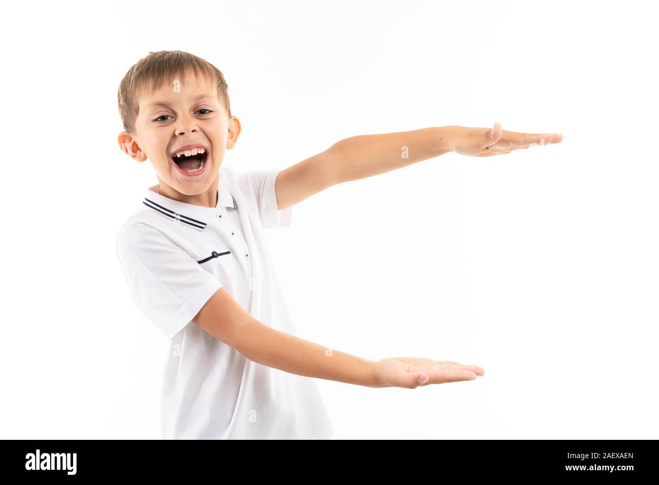 cute boy with bangs in a white t-shirt holds something in his hands on ...