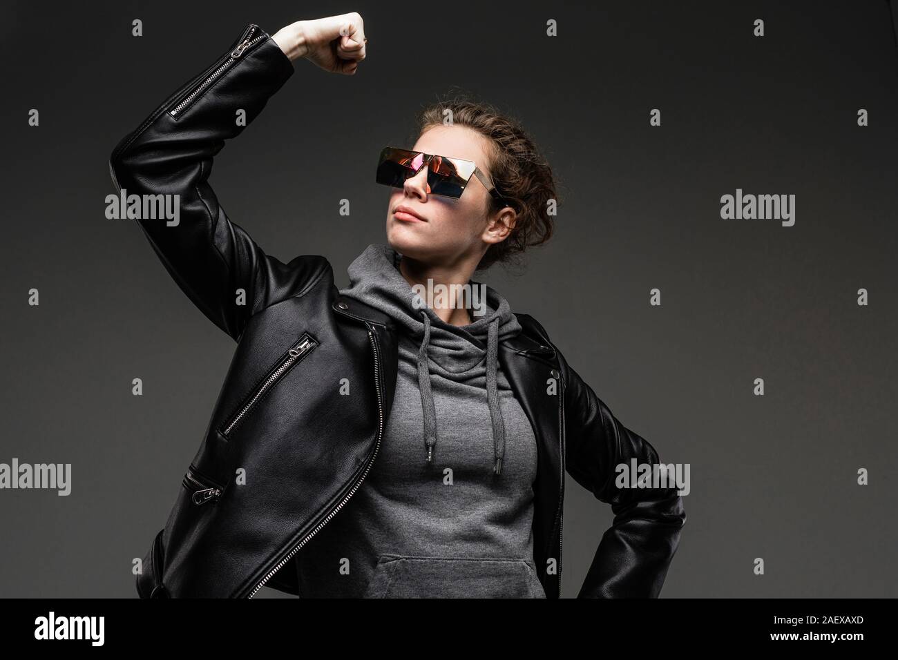 A young girl with rough facial features in a black jacket shows her ...