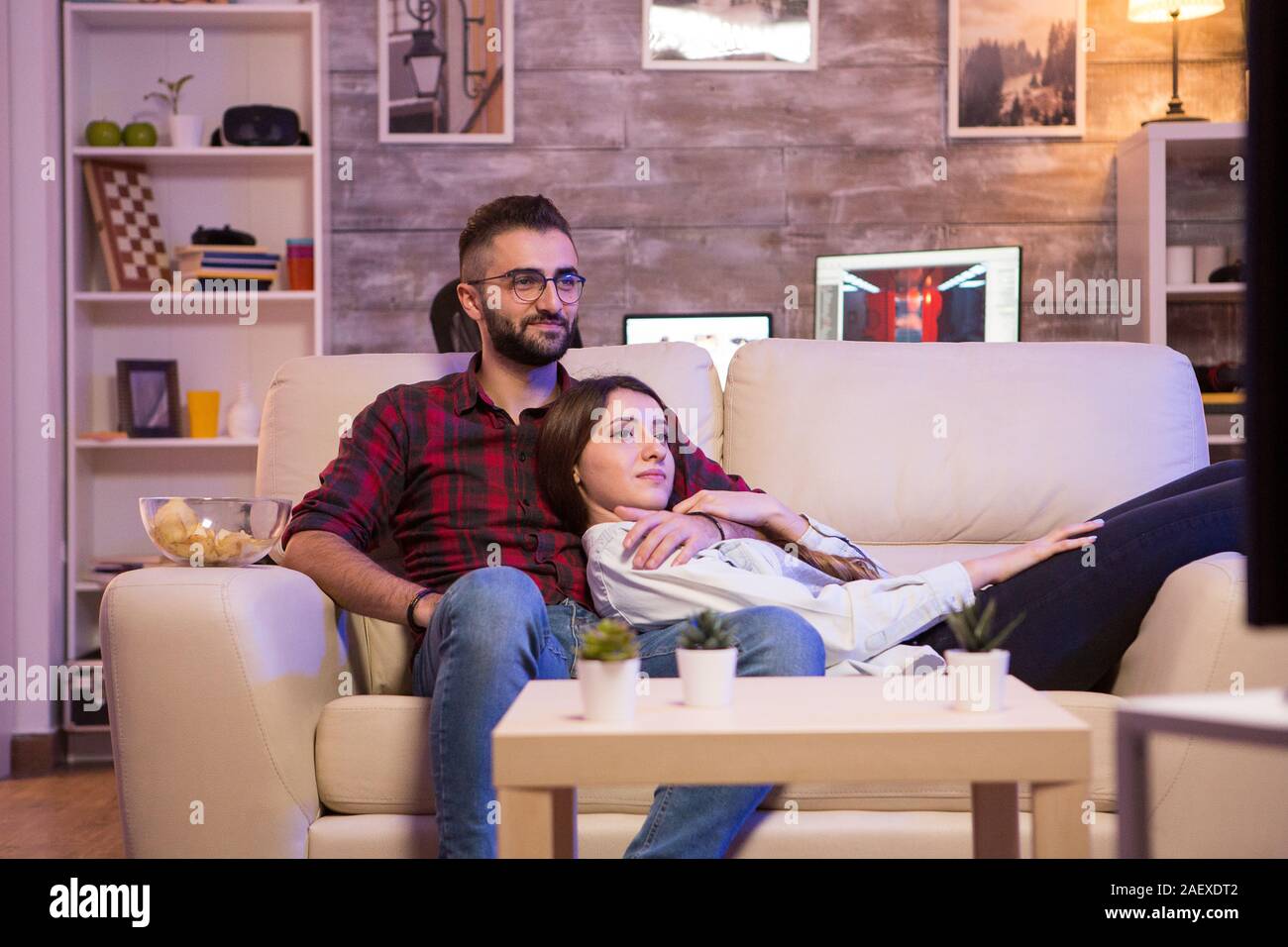 Beautiful young couple watching their favorite tv show while relaxing ...