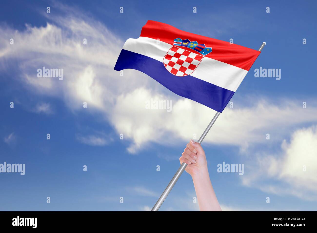 Female hand is waving Croatia Flag against blue sky with clouds ...