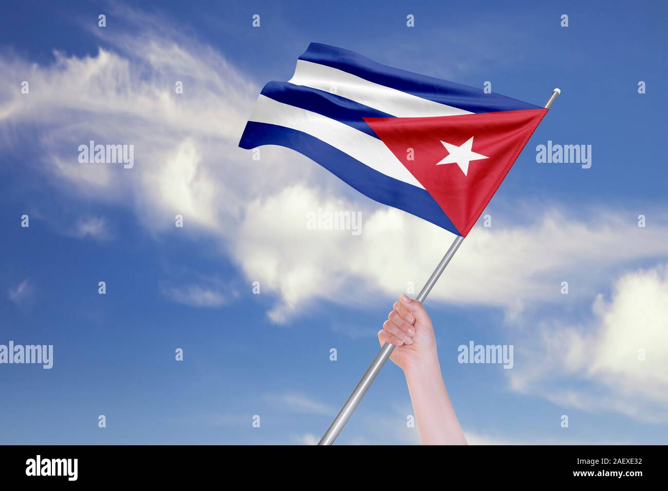 Female hand is waving Cuban Flag against blue sky with clouds ...