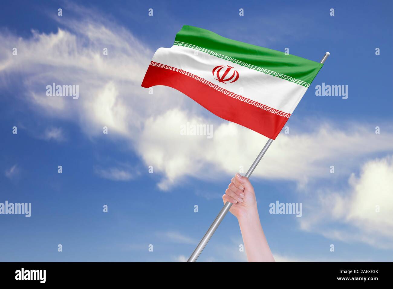 Female hand is waving Iranian Flag against blue sky with clouds ...