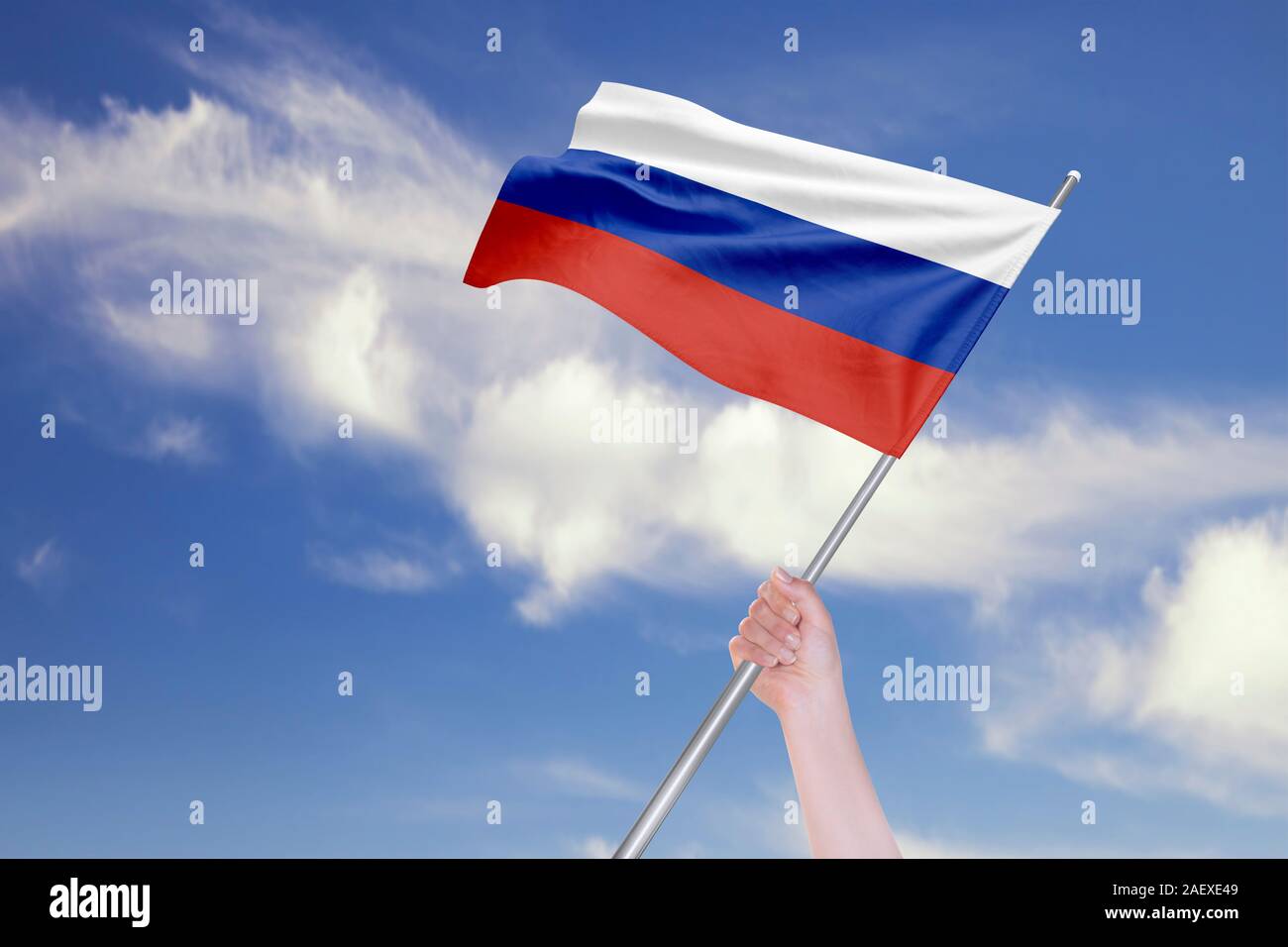 Female hand is waving Russian Flag against blue sky with clouds ...