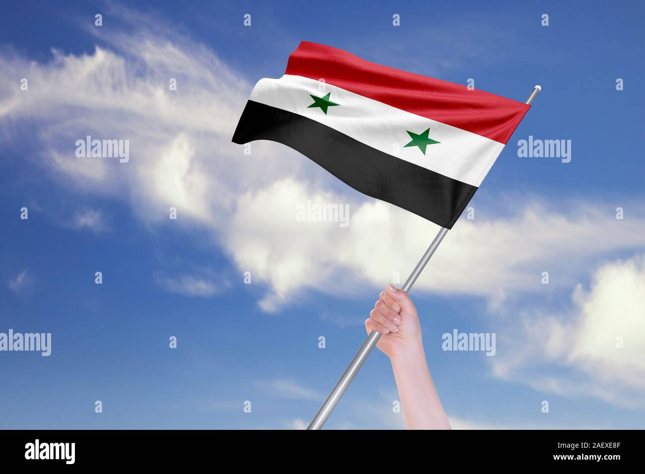 Female hand is waving Syrian Flag against blue sky with clouds ...