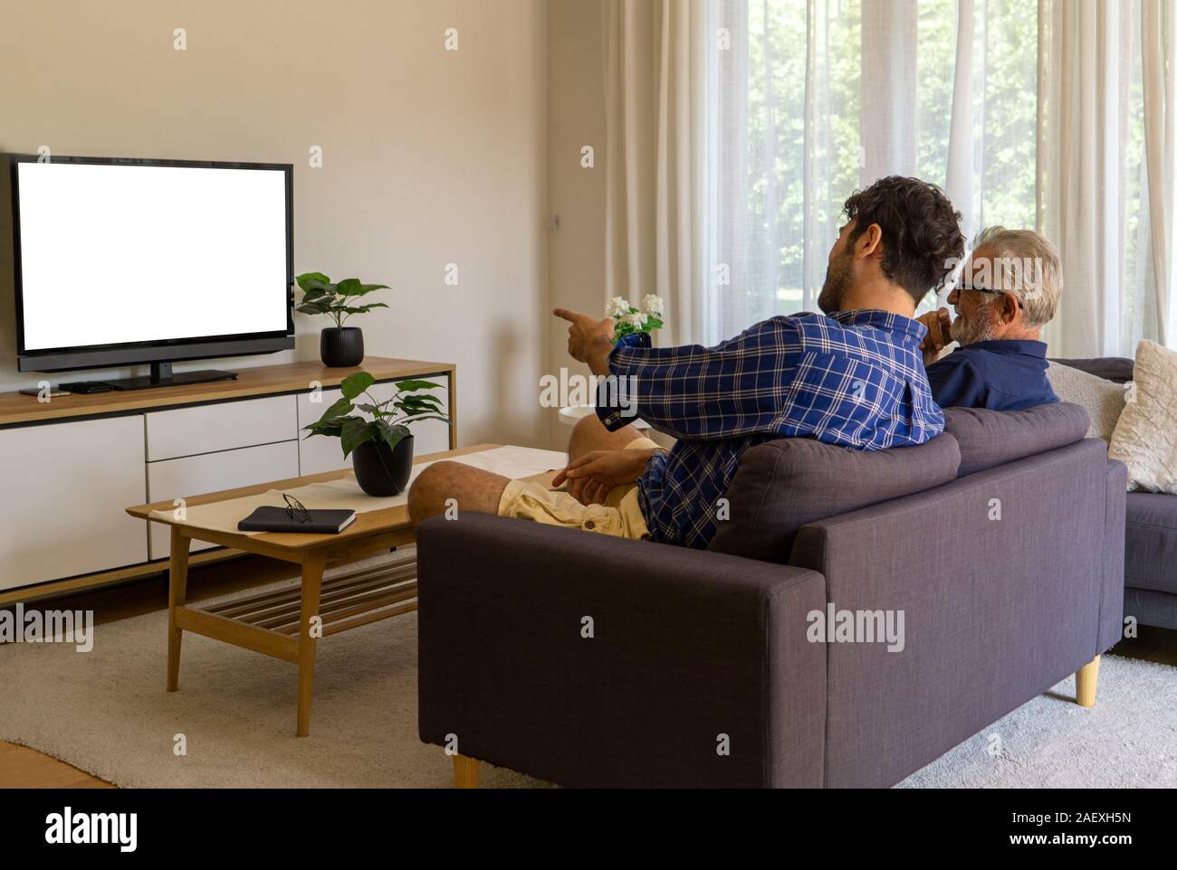 Middle aged male showing watching TV with his father in livingroom ...