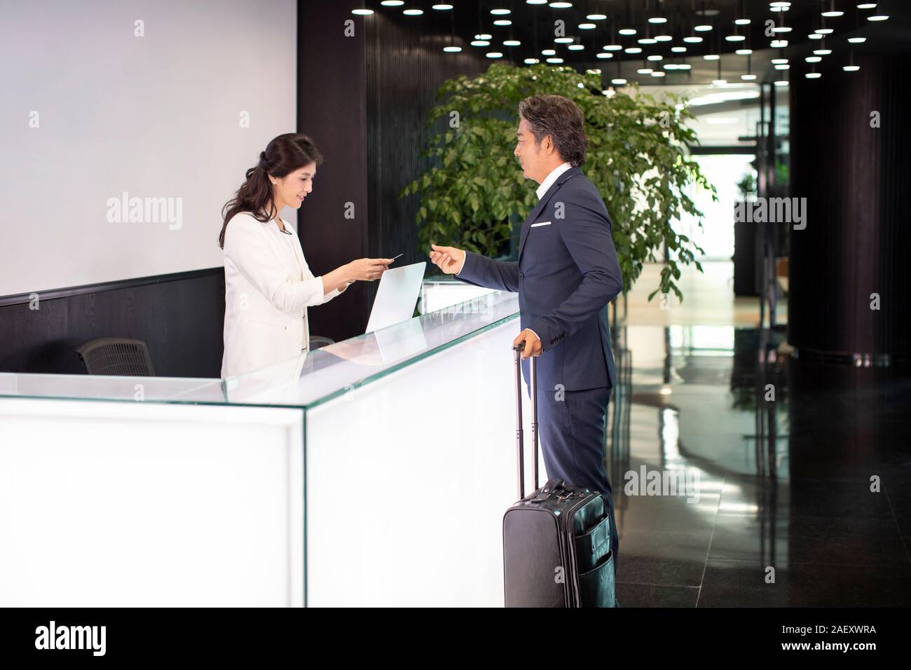 Mature businessman giving business card to receptionist Stock Photo - Alamy