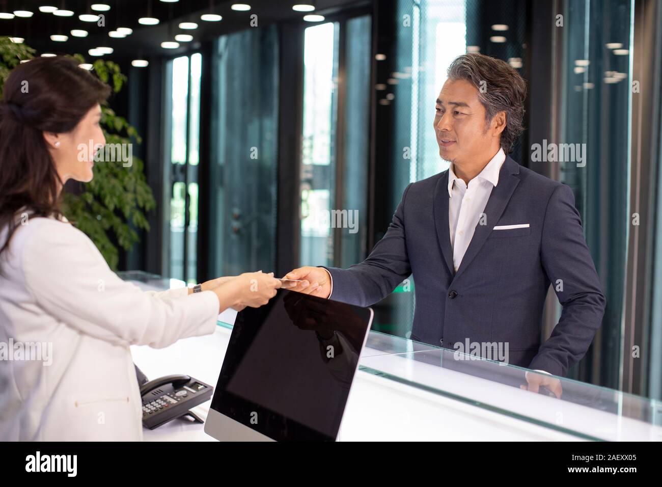 Receptionist giving business card to businessman Stock Photo - Alamy