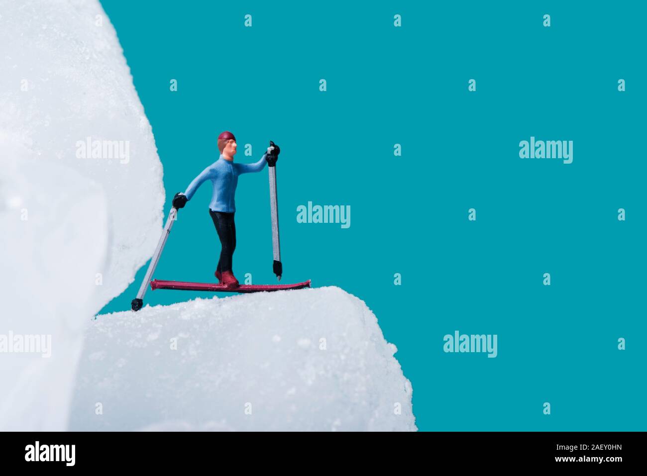 closeup of a miniature skier on an ice landscape against a blue ...