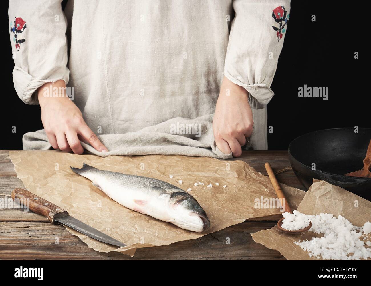 fresh whole sea bass fish lies on the table, cooking process, dark ...
