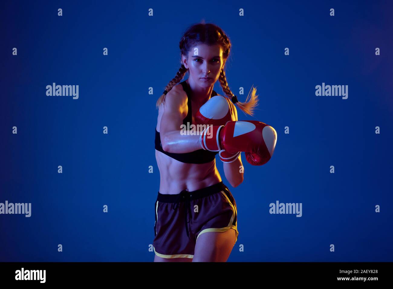 On the run. Fit caucasian woman in sportswear boxing on blue studio ...