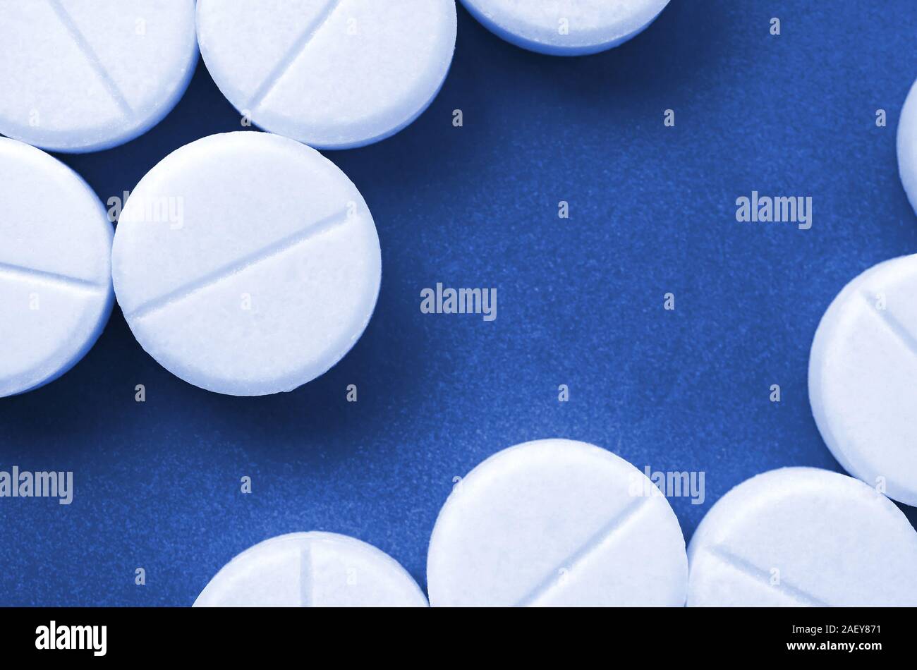 A few white tablets lie on a bright phantom classic blue color ...