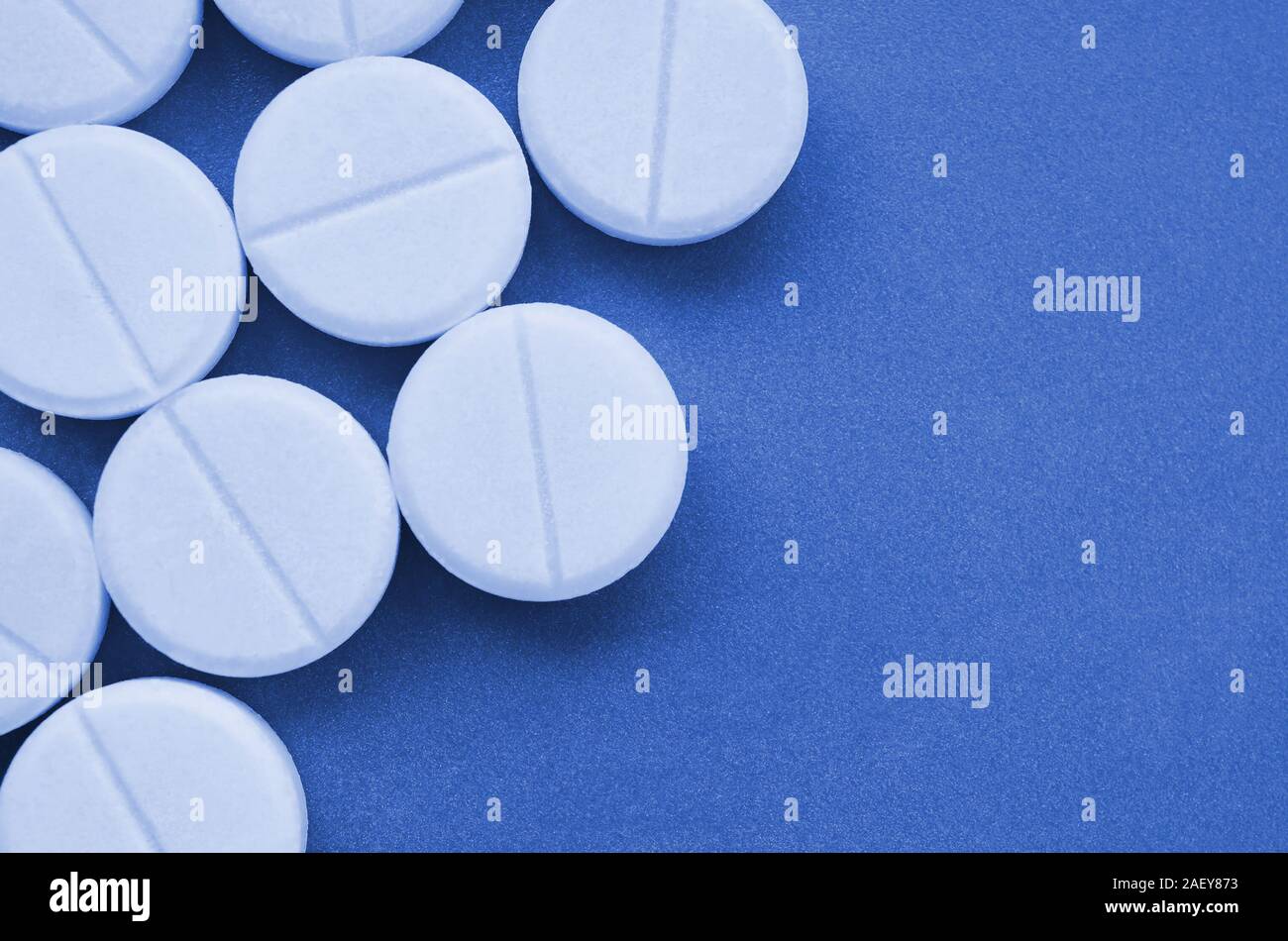 A few white tablets lie on a bright phantom classic blue color ...