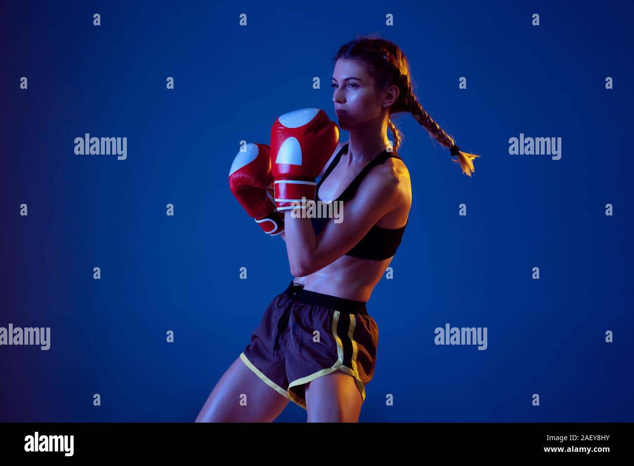 Activity. Fit caucasian woman in sportswear boxing on blue studio ...