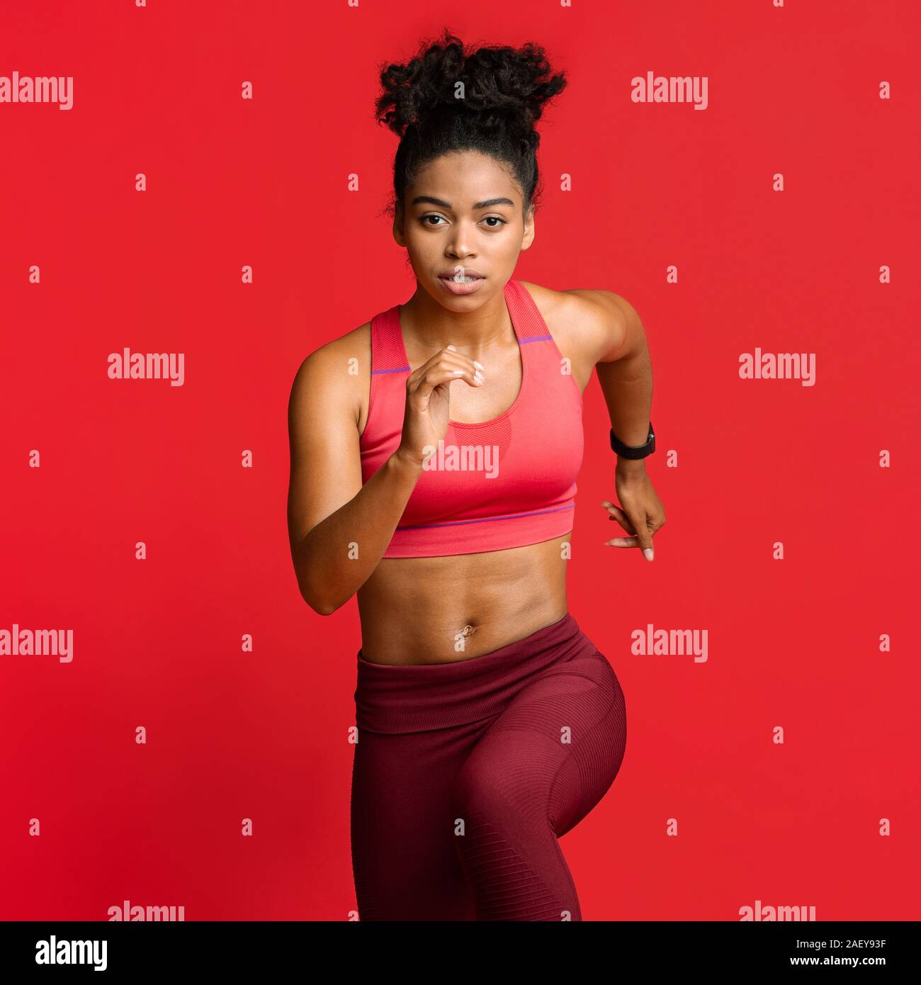 Portrait of running black fitness model over red studio background ...