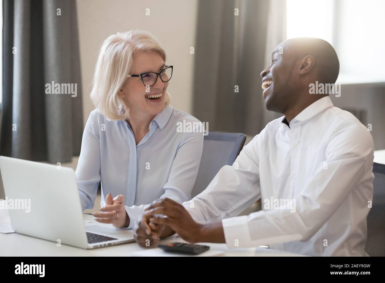 Smiling diverse colleagues laugh cooperating at laptop in office Stock ...