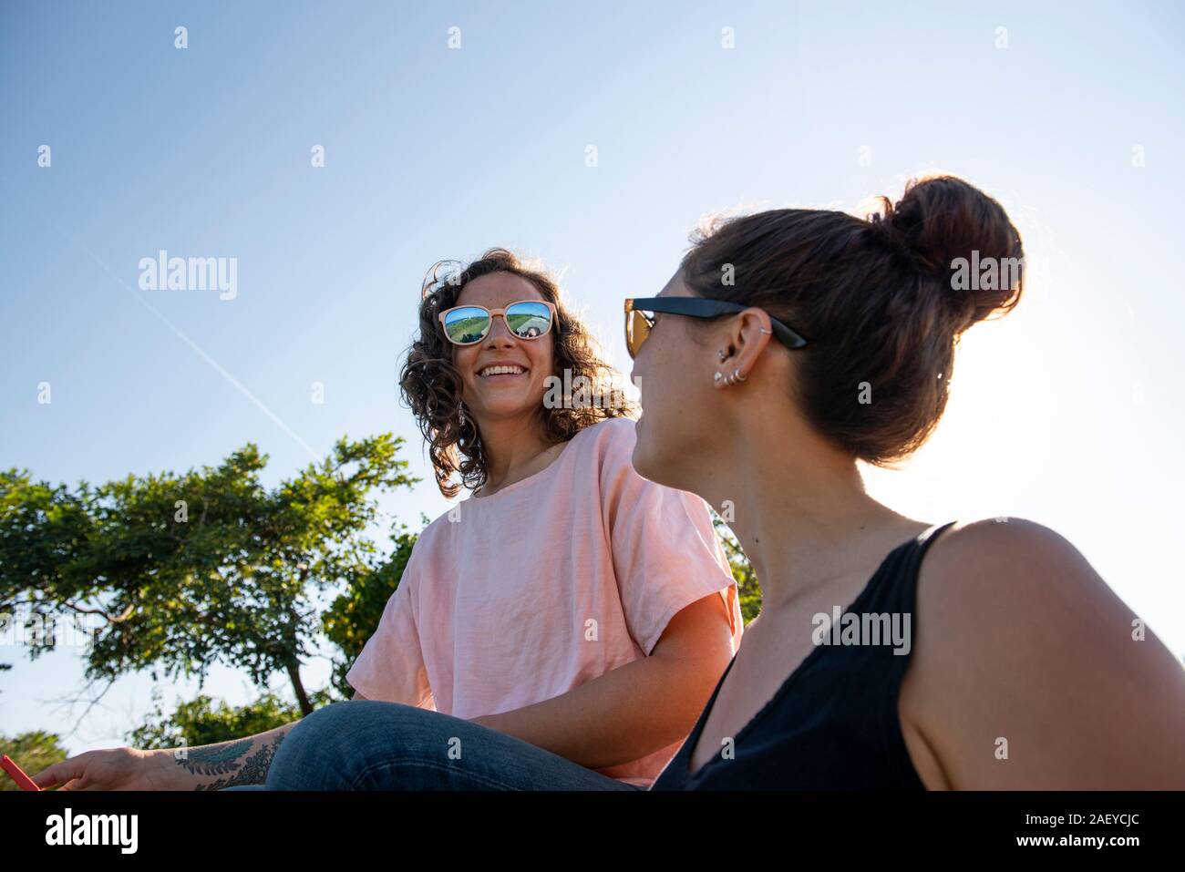 Two friends sitting in the sunshine smiling Stock Photo - Alamy