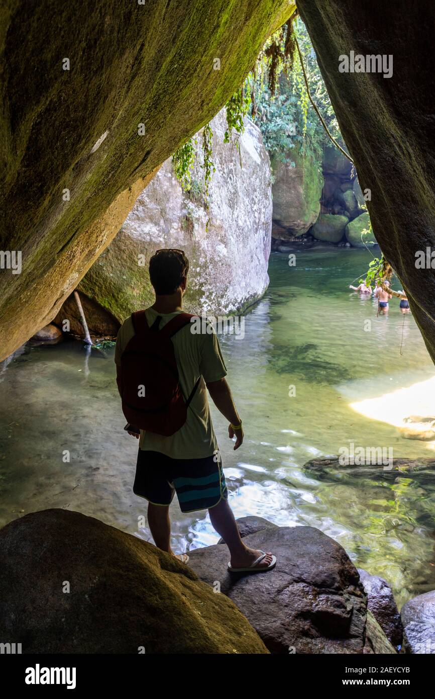 Man inside cave looking into beautiful green river in Serra dos Órgãos ...