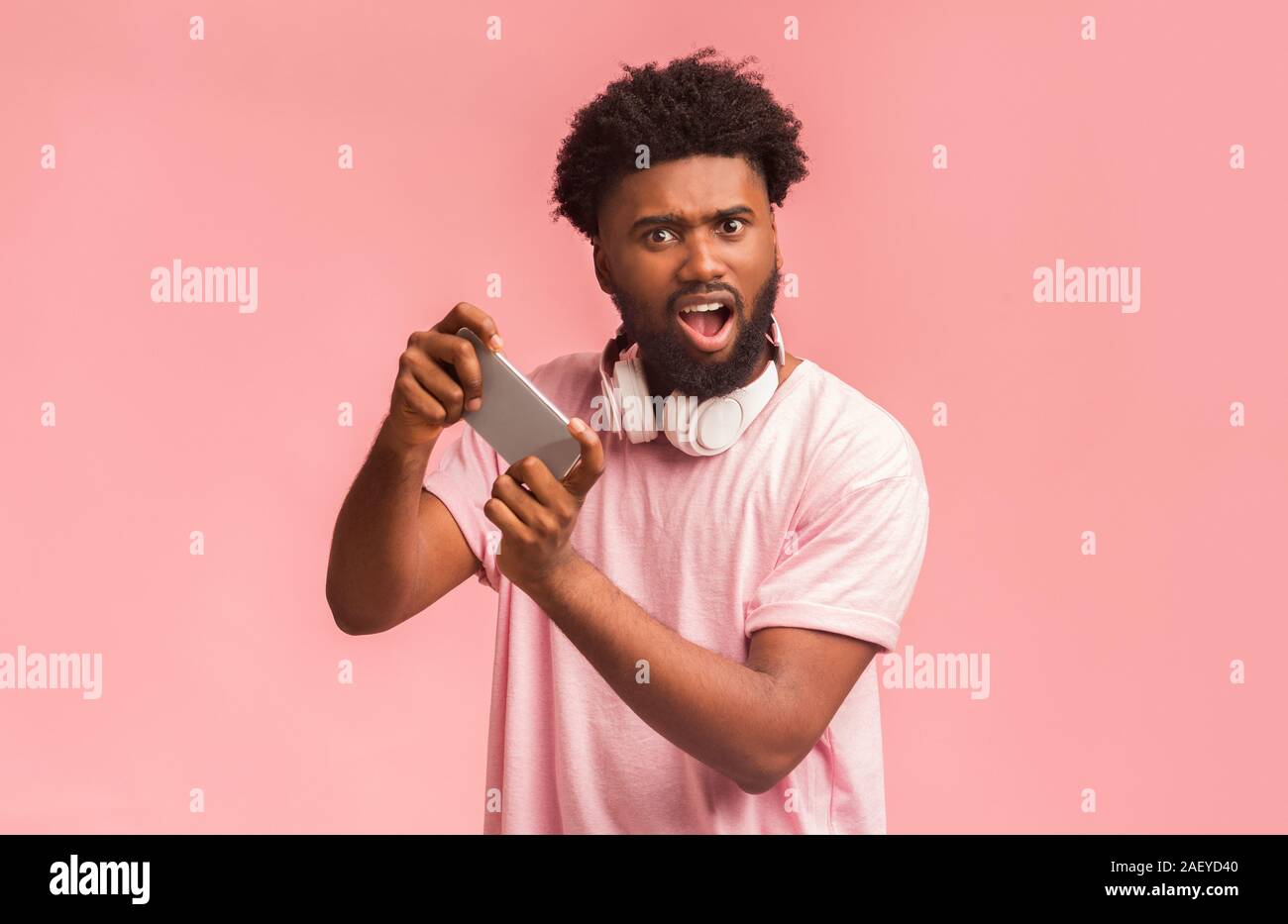 Game addiction. Emotional african american guy holding phone and ...