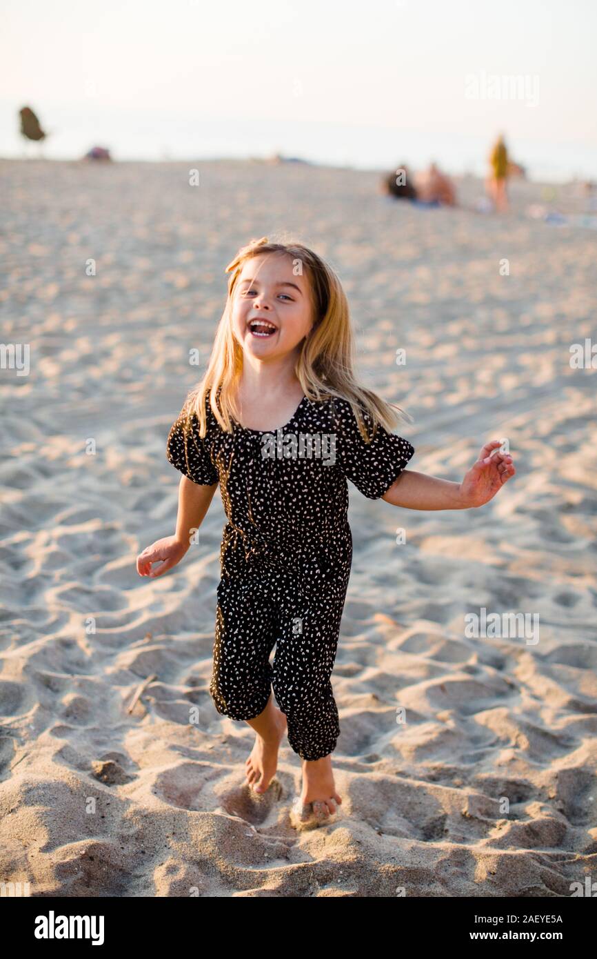 Young Girl Laughing and Playing on Beach at Sunset Stock Photo - Alamy
