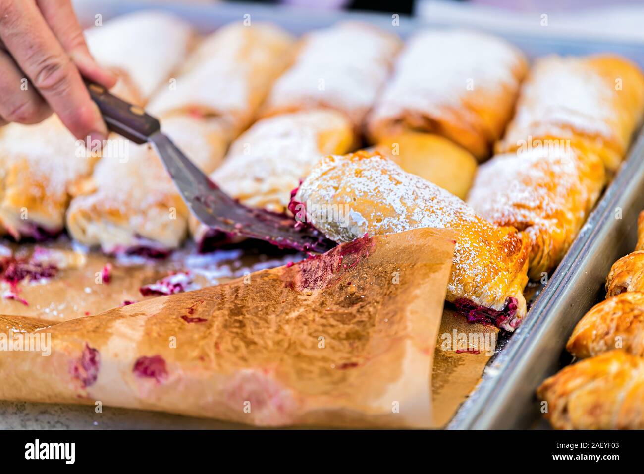 Hand picking up dessert pastry from tray display in street food farmers ...