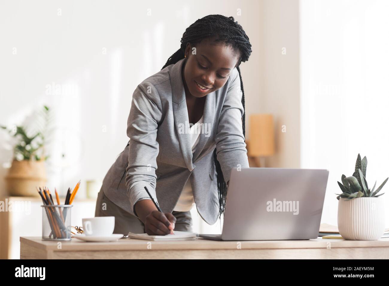Working process. Busy afro secretary taking notes while standing up ...