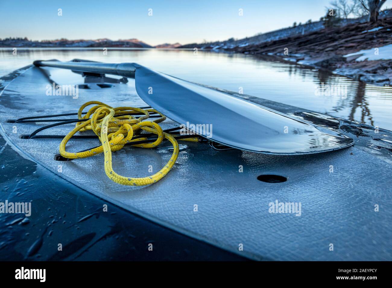 Winter dusk after paddling workout - yellow rope and paddle on an icy ...