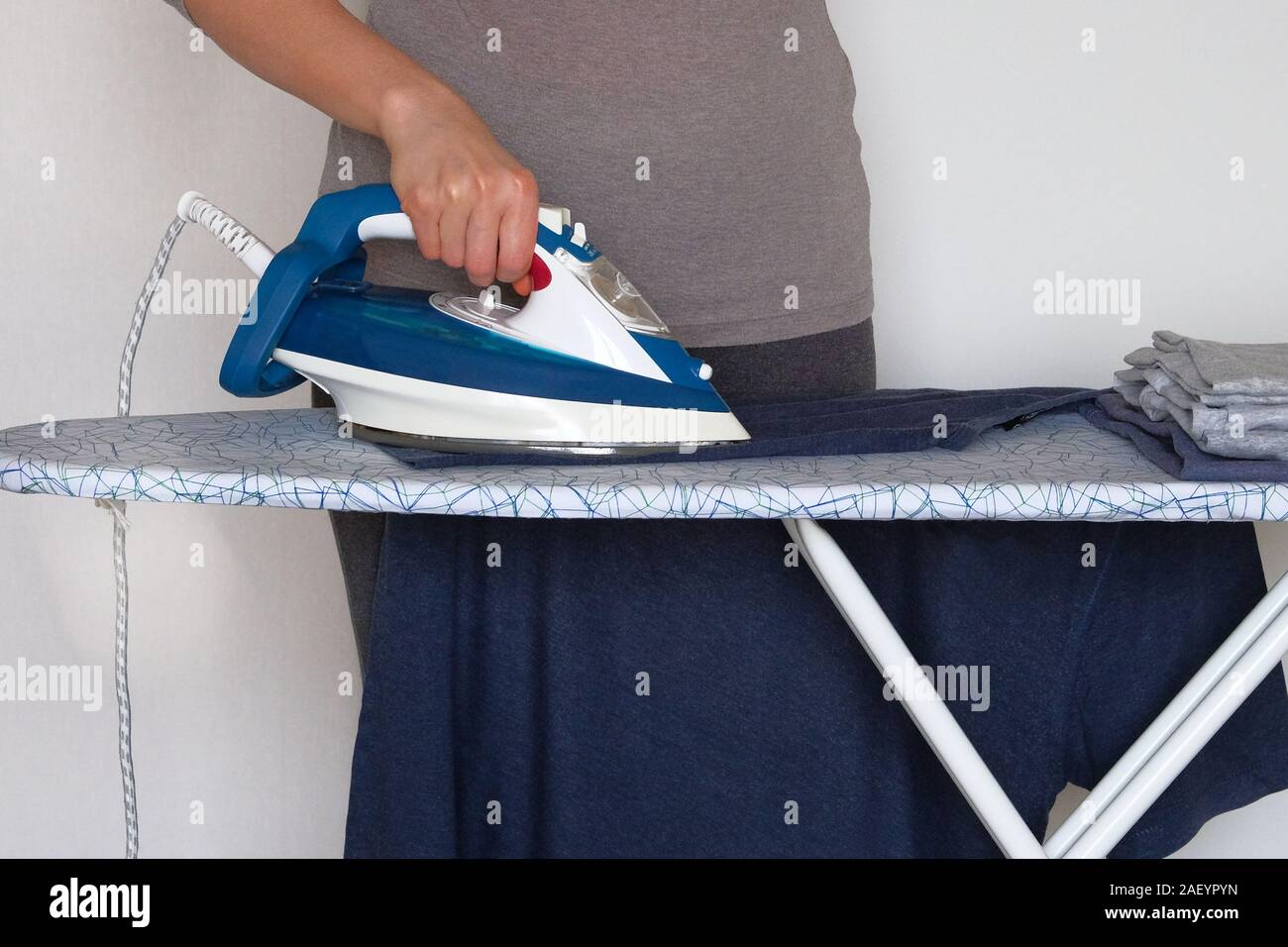 Clothing ironing at home. Young girl is ironing garments at home ...