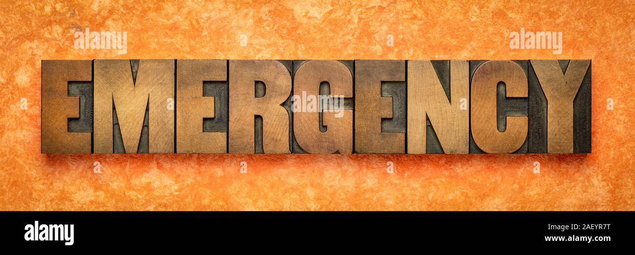 emergency word banner in letterpress wood type against orange textured ...