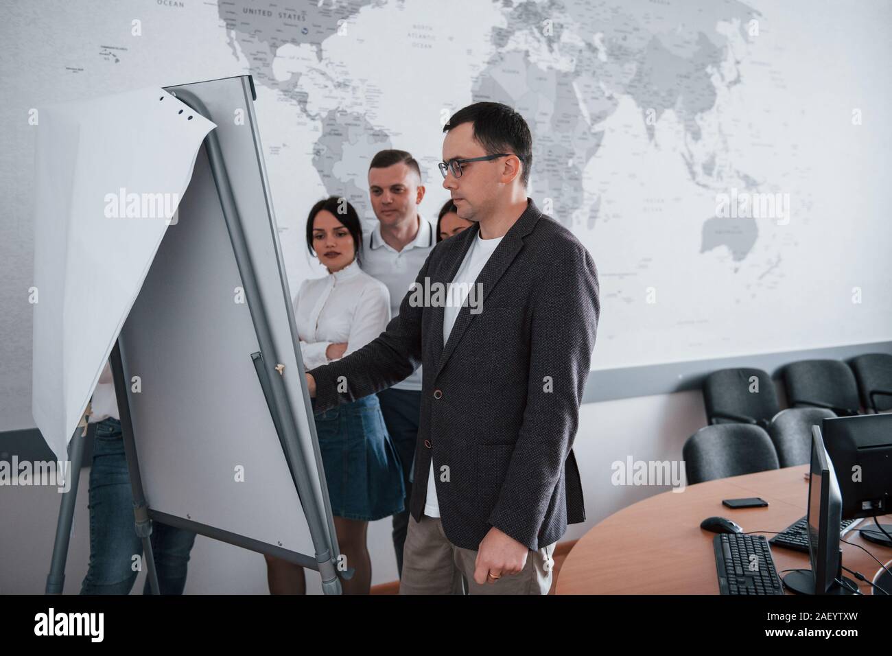 Standing near whiteboard. Business people and manager working on their ...